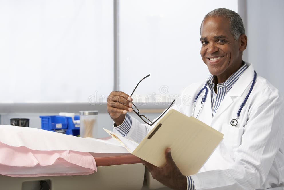 Male Doctor in Surgery Reading Patient Notes Stock Photo - Image of ...