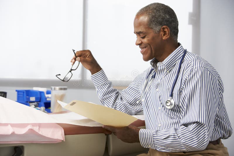Male Doctor in Surgery Reading Patient Notes Stock Image - Image of ...
