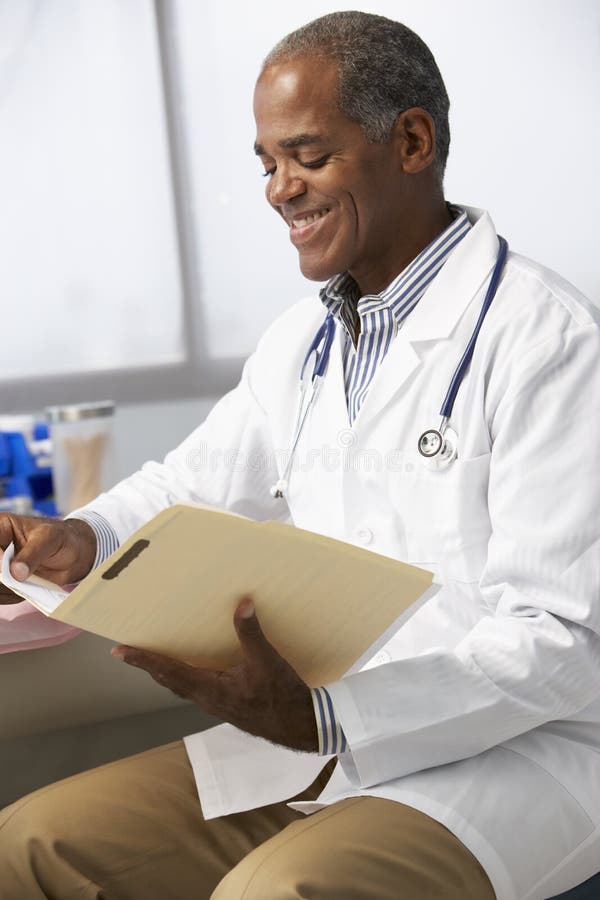 Male Doctor in Surgery Reading Patient Notes Stock Image - Image of ...