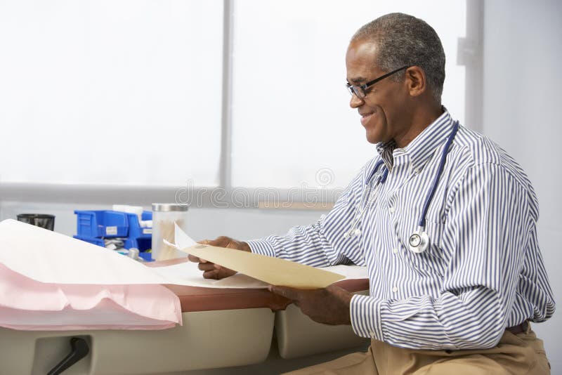 Male Doctor in Surgery Reading Patient Notes Stock Image - Image of ...