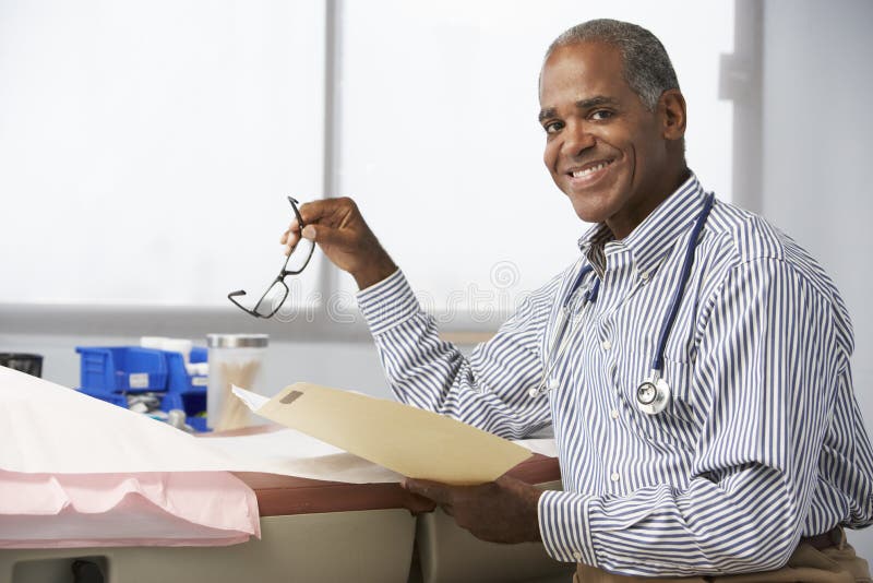 Male Doctor in Surgery Reading Patient Notes Stock Image - Image of ...