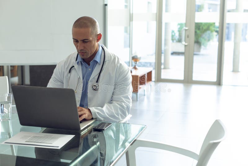 Male Doctor Using Laptop at Table in the Hospital Stock Photo - Image ...