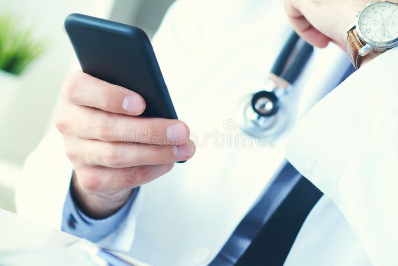 Male Doctor in White Coat is Using a Modern Smartphone Device with ...