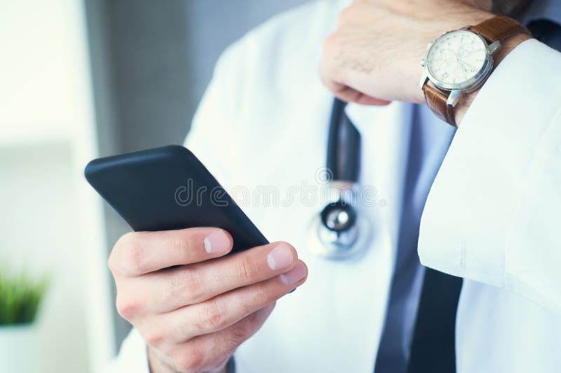 Male Doctor in White Coat is Using a Modern Smartphone Device with ...