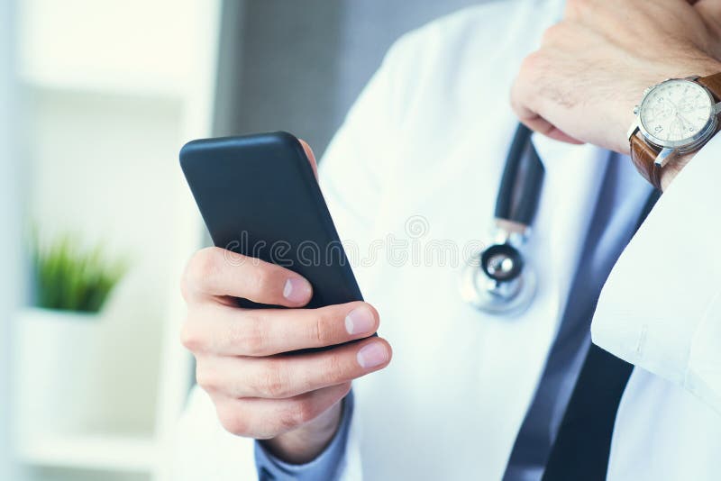 Male Doctor in White Coat is Using a Modern Smartphone Device with ...