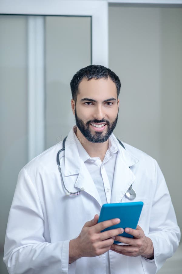 Male Doctor in a White Robe Holding a Tablet and Smiling Stock Image ...