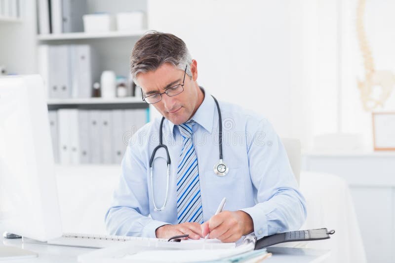 Male Doctor Writing on Paper at Table Stock Photo - Image of document ...