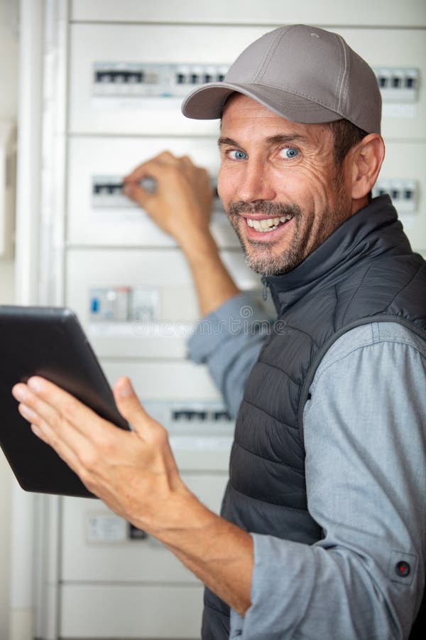 Male Electrician Holding Tablet and Working on Fuse Box Stock Image ...