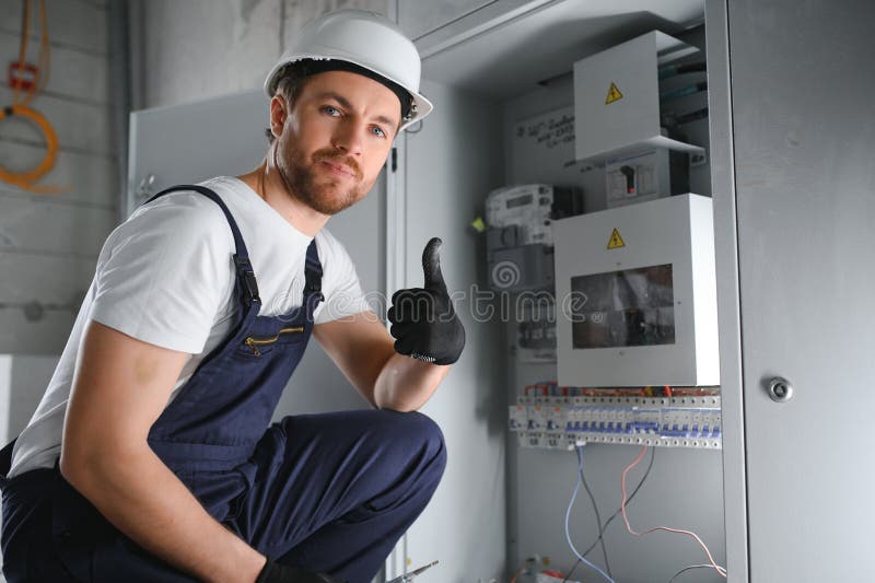 A Male Electrician Works in a Switchboard with an Electrical Connecting ...