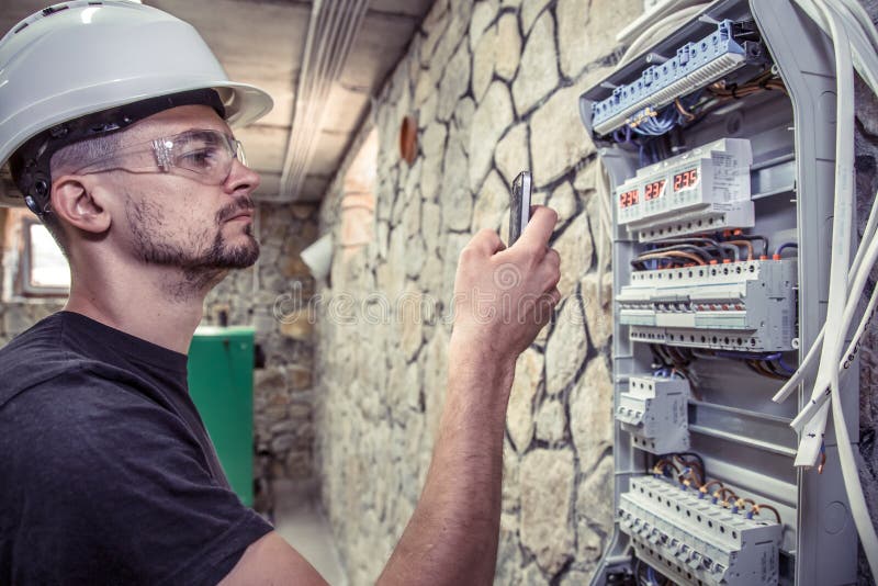A Male Electrician Works in a Switchboard with an Electrical Con Stock ...