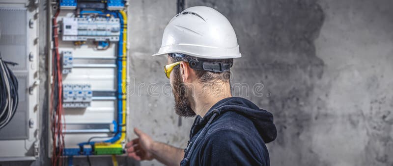 A Male Electrician Works in a Switchboard with an Electrical Connecting ...