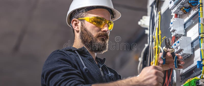 A Male Electrician Works in a Switchboard with an Electrical Connecting ...