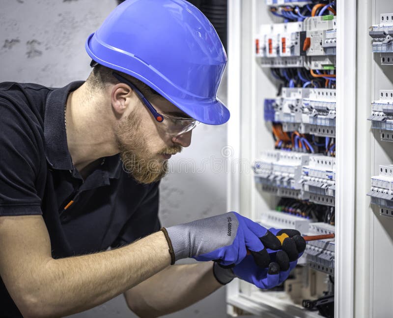 A Male Electrician Works in a Switchboard with an Electrical Connecting ...