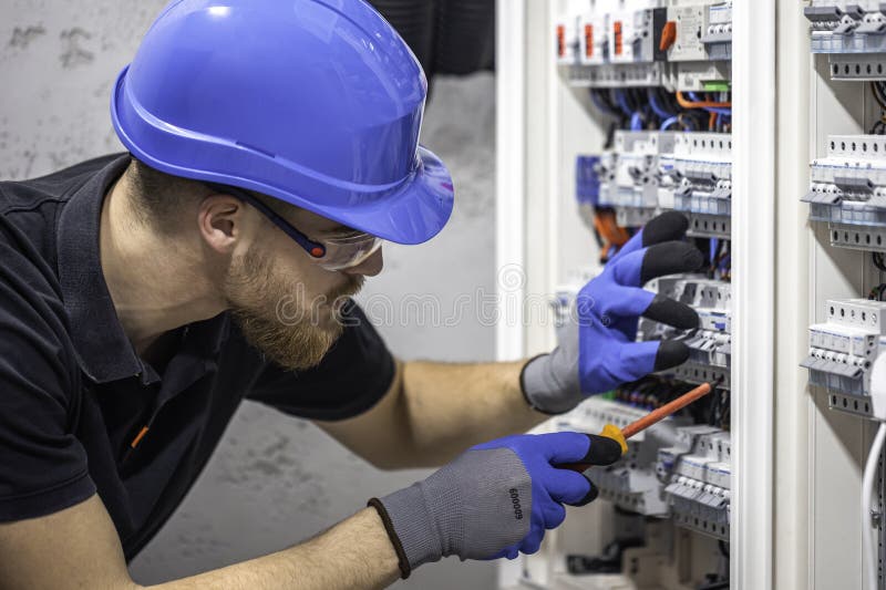 A Male Electrician Works in a Switchboard with an Electrical Connecting ...