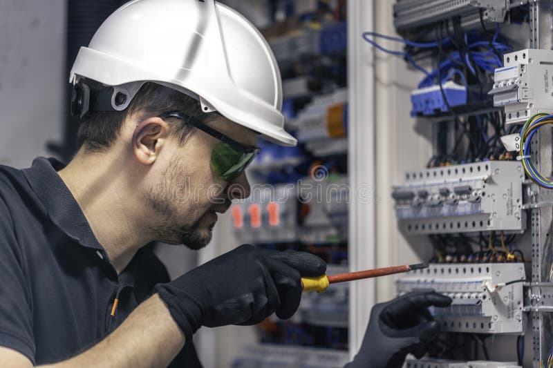 A Male Electrician Works in a Switchboard Using an Electrical ...