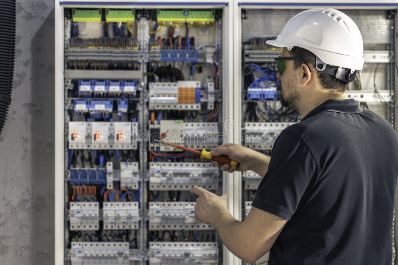 A Male Electrician Works in a Switchboard Using an Electrical ...