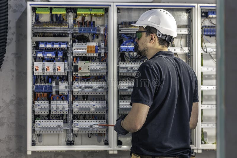 A Male Electrician Works in a Switchboard Using an Electrical ...