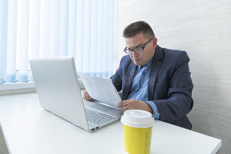 Male Employee in a Blue Jacket Works with Documents and on a Computer ...