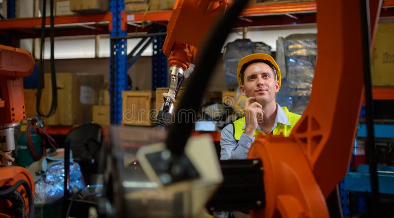 A Male Engineer Checking the Operation of a Welding Robot. Stock Photo ...