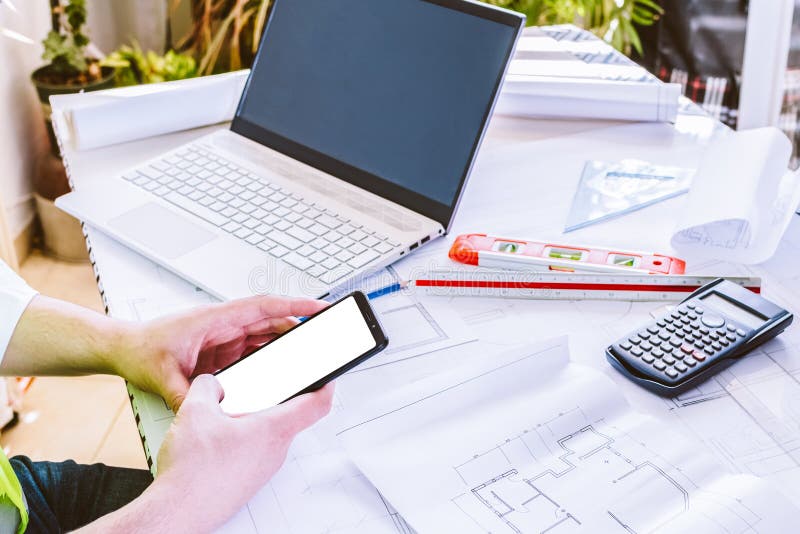 Male Engineer Hands Using a Mobile Phone while Working on Blueprints at ...