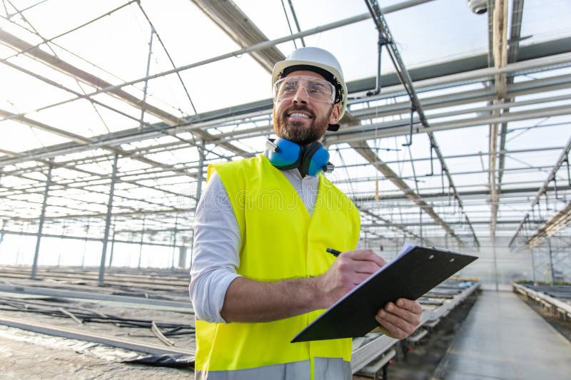 Male Engineer in Hardhat and Protective Glasses Inspecting Construction ...