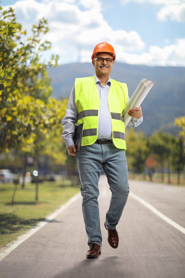 Male Engineer Holding Blueprints and Walking Stock Photo - Image of ...