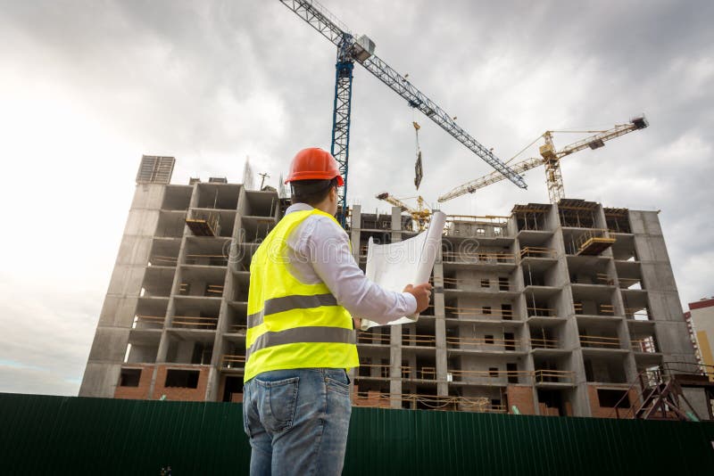 Male Engineer in Safety Vest and Hardhat Looking at Construction of New ...