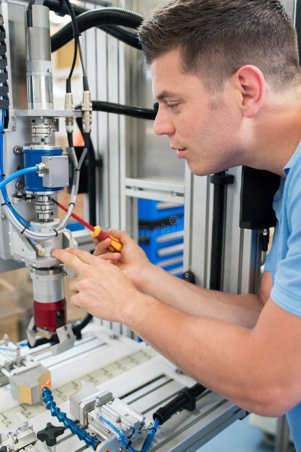 Male Engineer with Technical Drawing Operating CNC Machine in Fa Stock ...