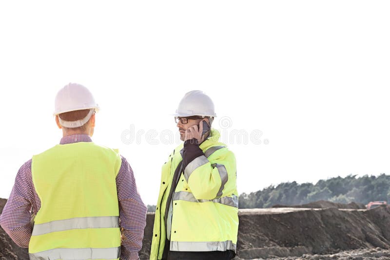 Male Engineer Using Mobile Phone while Standing with Colleague at ...