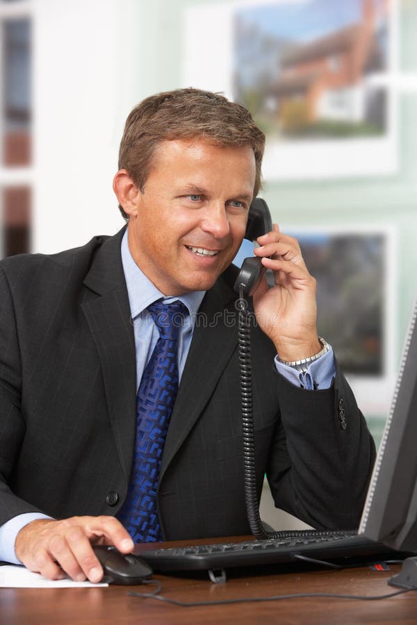 Male Estate Agent Talking on Phone at Desk Stock Image - Image of ...