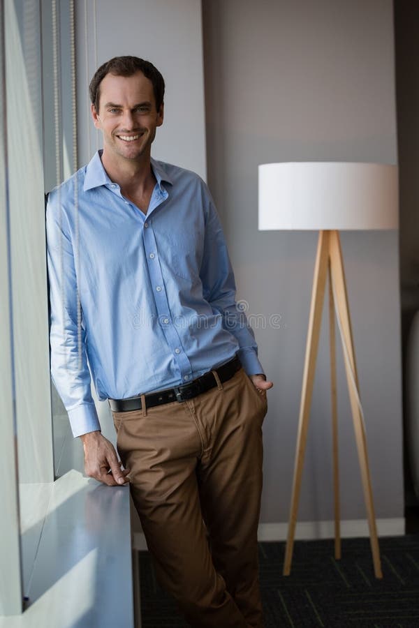 Male Executive Standing in Office with Colleagues in Background Stock ...