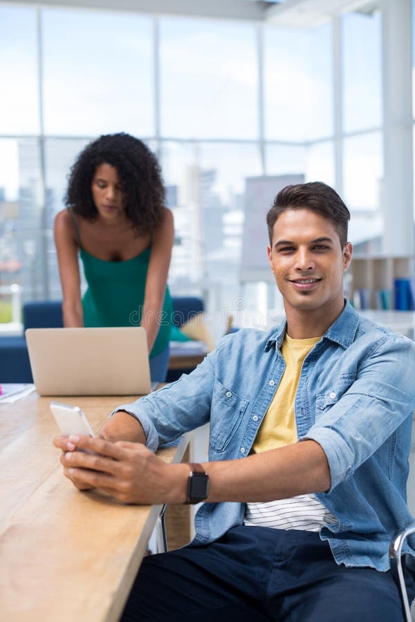 Male Executive Using Mobile Phone while Female Executive Working on ...