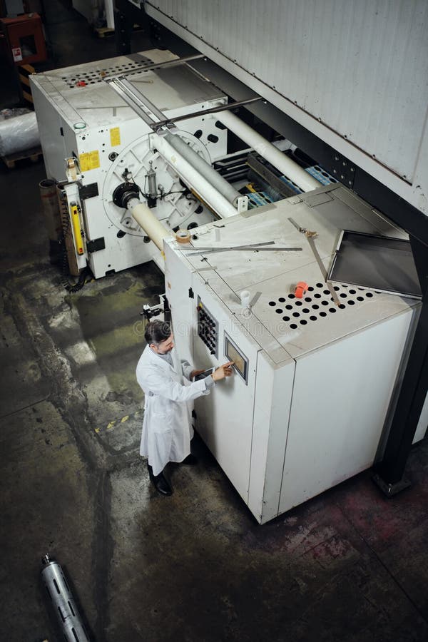 Engineer Working at the Factory Surrounded with Machinery, Checking ...