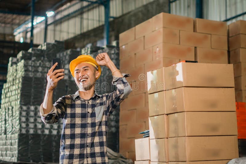 Male Factory Worker Excited while Looking at Cell Phone while Working ...