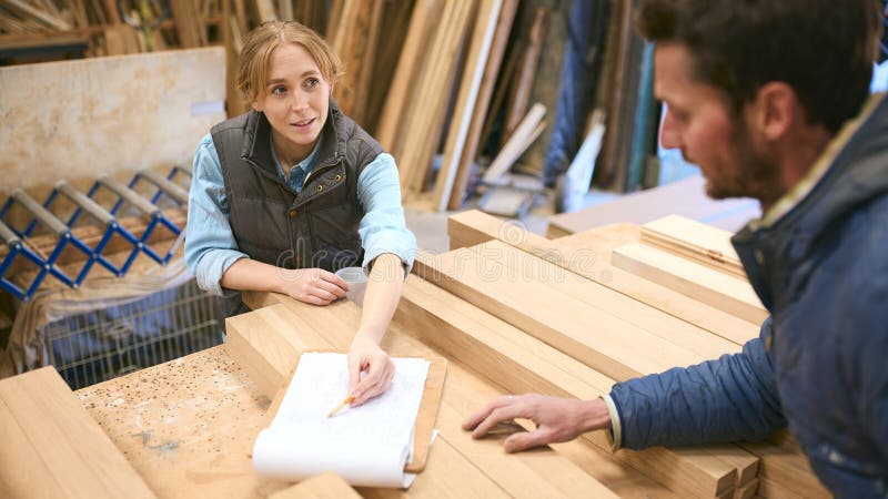 Male and Female Carpenter Working in Woodwork Workshop Discussing Plan ...