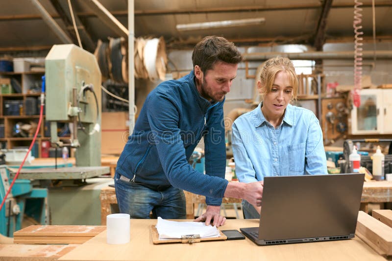 Male and Female Carpenters Working in Woodwork Workshop Using Laptop ...