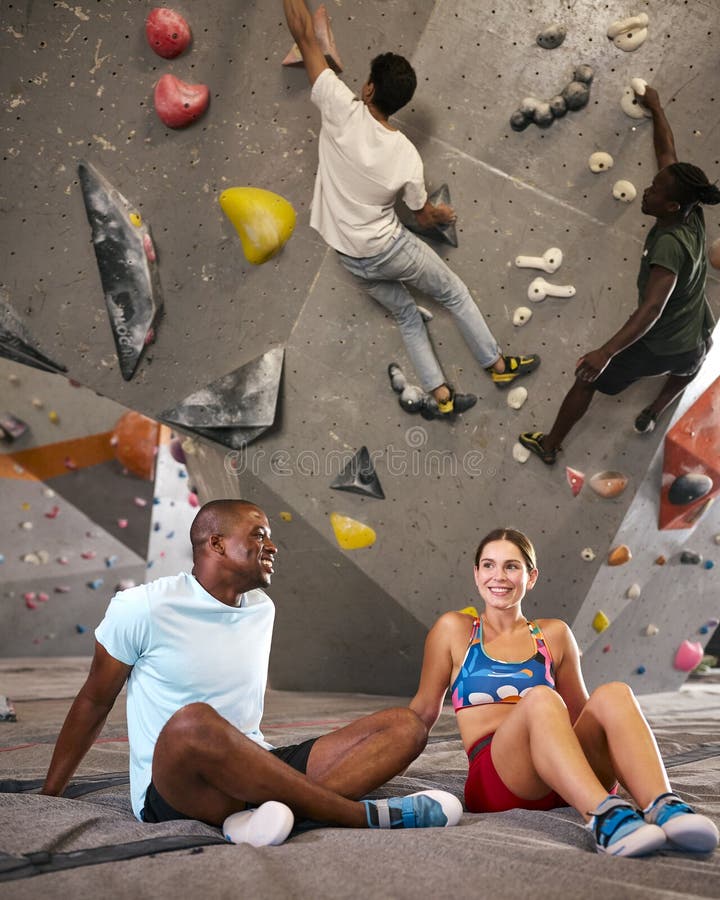 Male and Female Climbers Taking a Break and Talking by Climbing Wall in ...