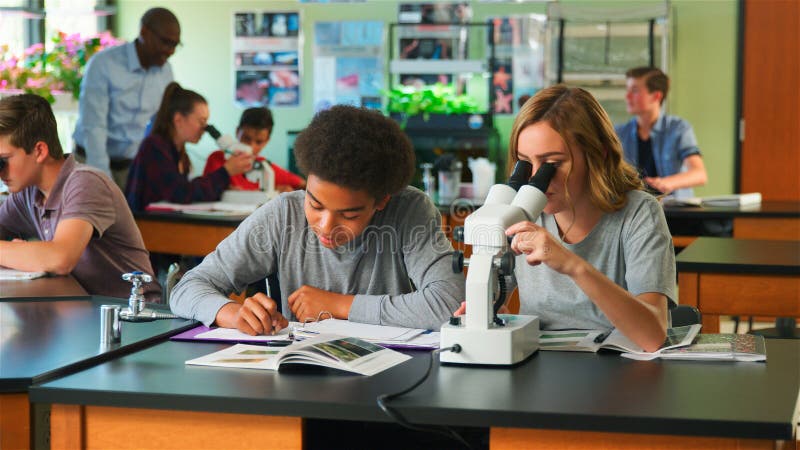 Male and Female High School Students Using Microscope in Biology Class ...