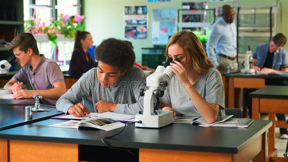 Male and Female High School Students Using Microscope in Biology Class ...