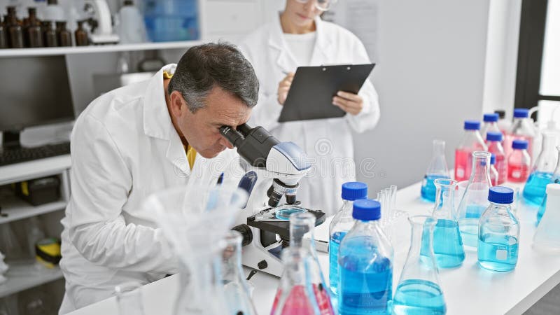Male and Female Scientists Working Together in Lab, Serious ...