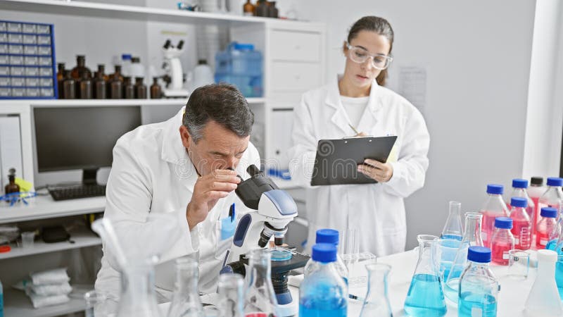 Male and Female Scientists Working Together in Lab, Serious ...