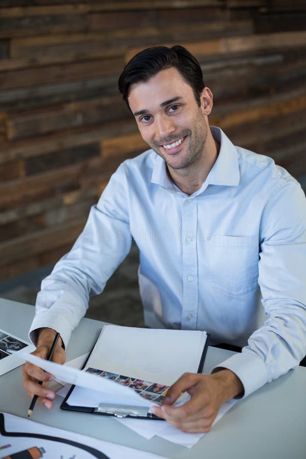 Male Graphic Designer Holding Photos in Office Stock Photo - Image of ...
