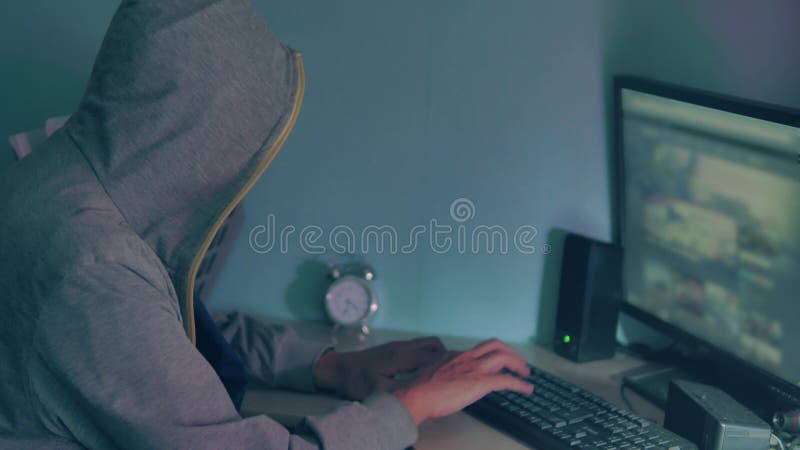 Male Hacker Working on a Computer. Man Hacker in Hood Hiding Indoor His ...