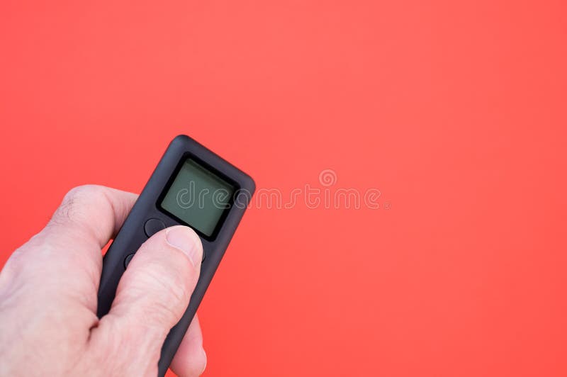 Male Hand Holding a Black Remote Controller on Red Background Stock ...