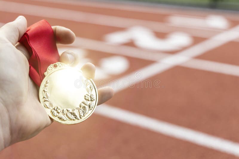 Male Hand Holding a Gold Medal in Front of a Running Track Stock Image ...