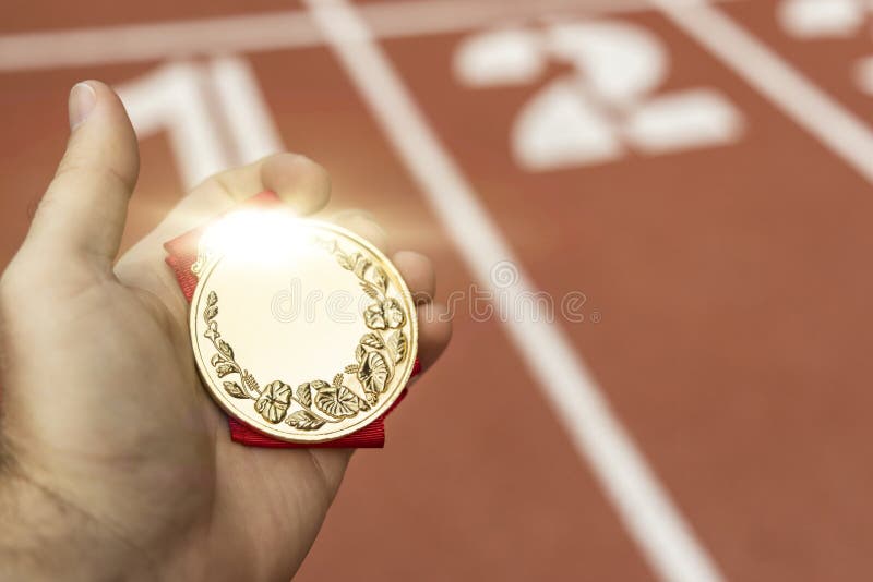 Male Hand Holding a Gold Medal in Front of a Running Track Stock Image ...