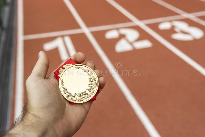 Male Hand Holding a Gold Medal in Front of a Running Track Stock Image ...