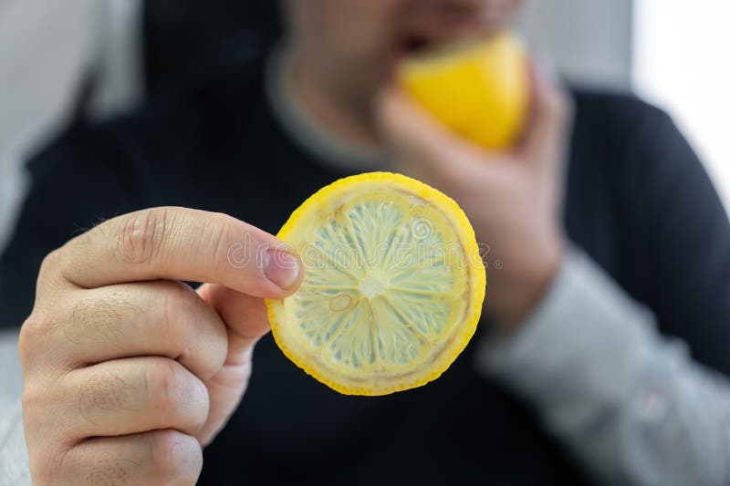 Male Hand Holds a Yellow Slice of Lemon,. Man Eats a Lemon Stock Photo ...