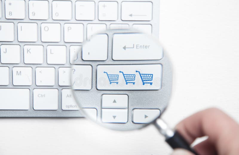 Male Hand Using Magnifying Glass. Shopping Carts on Computer Keyboard ...
