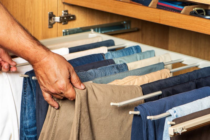 Male Hands Choosing a Pants from the Wardrobe among Several Visible ...